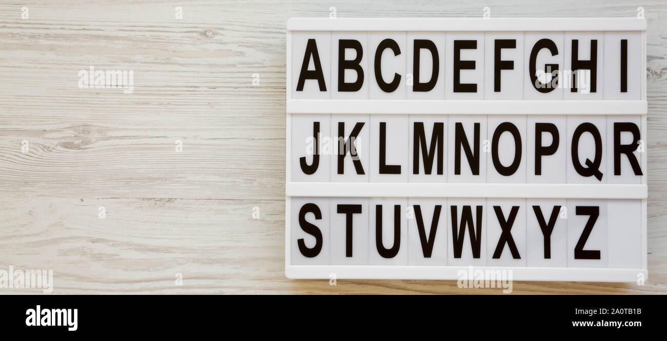 English alphabet on a modern board over white wooden surface, top view ...