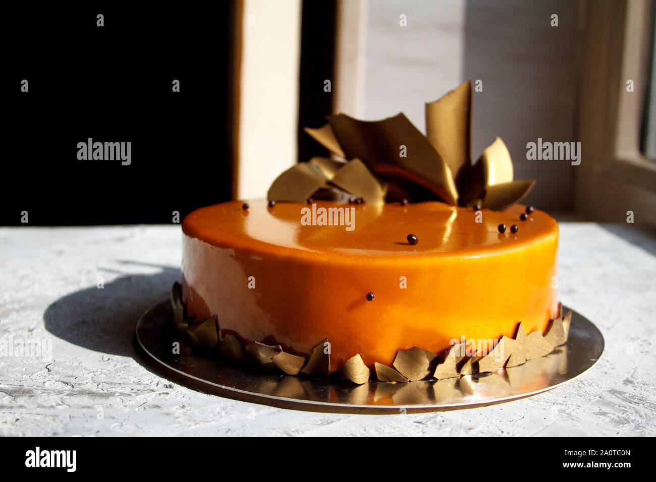 Caramel icing cake decorated with gold foil and chocolate drops on ...