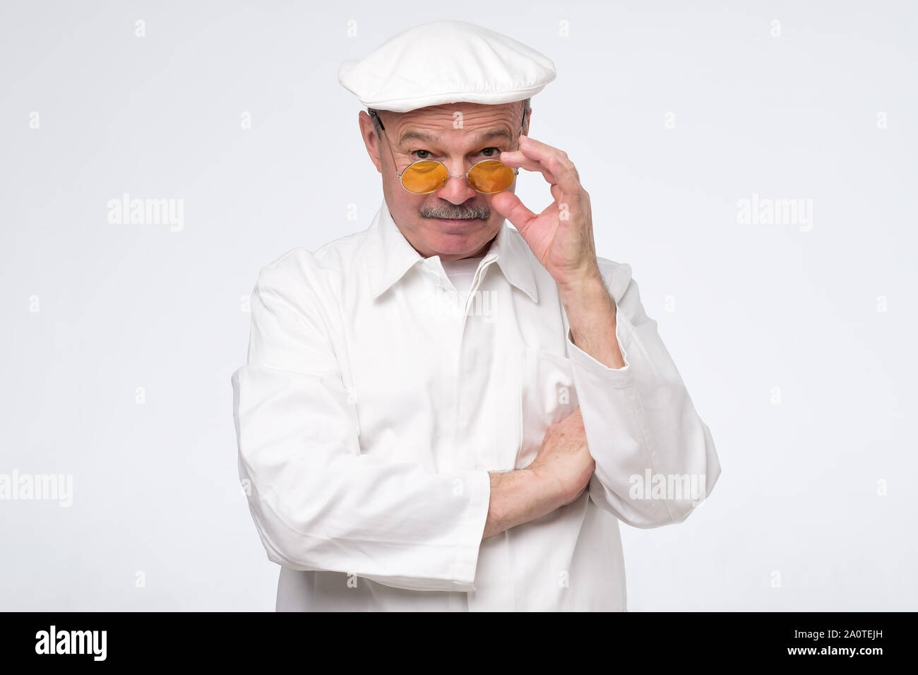 Experienced mature hispanic man in white uniform looking at camera ...