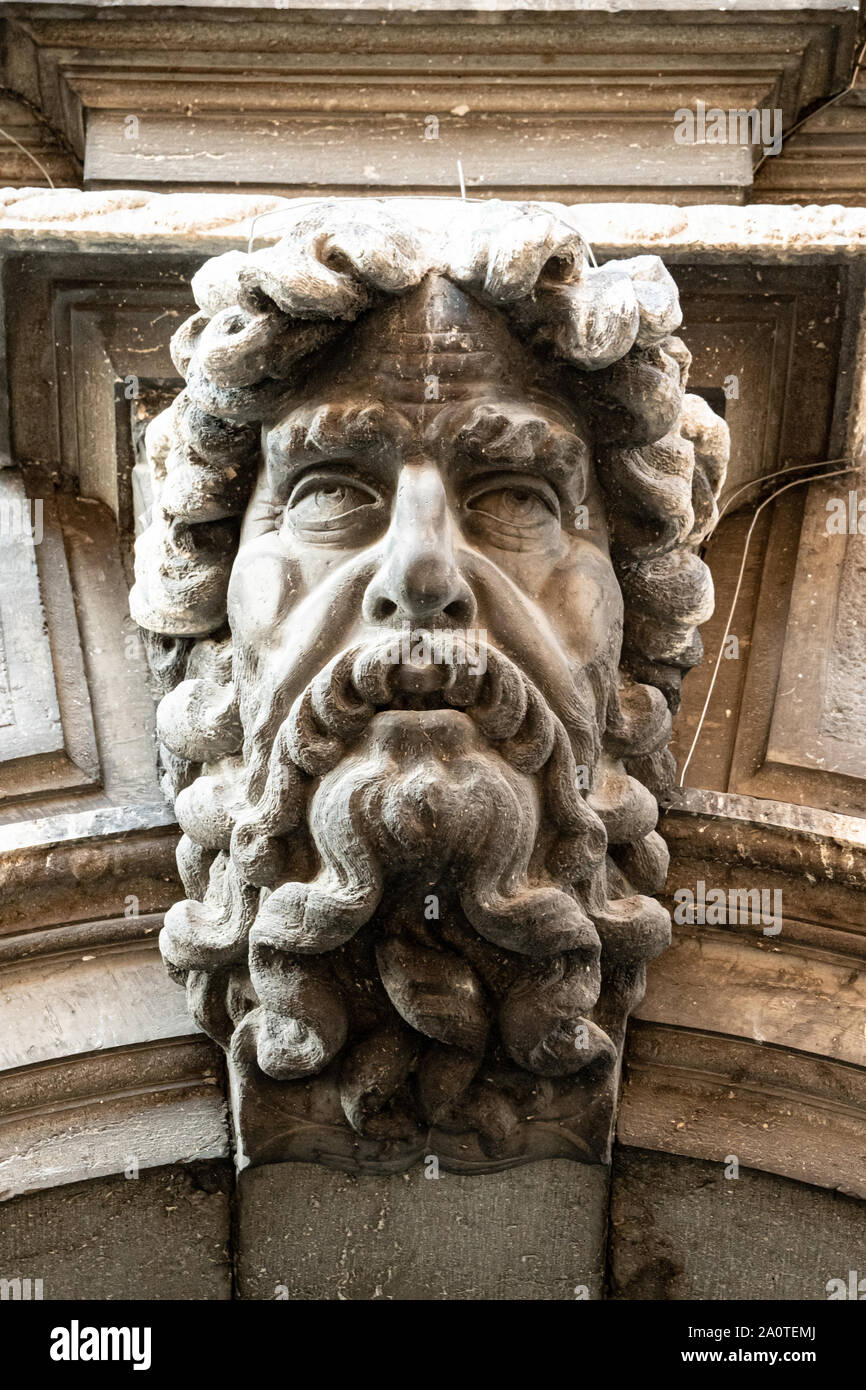 A carved stone head of a bearded man as the keystone to a building ...