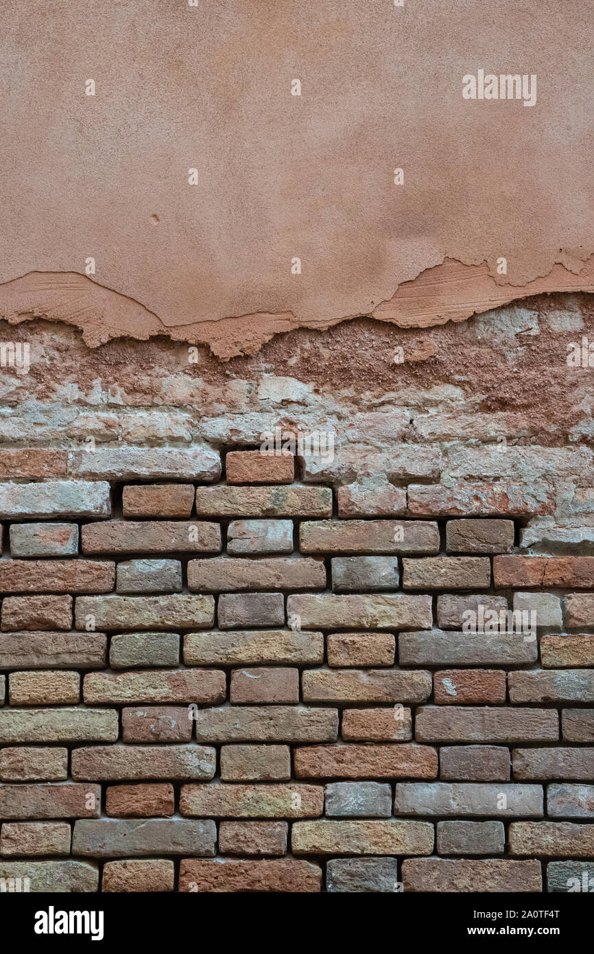 A wall, half bare brick and half brown plaster render, Venice, Italy ...