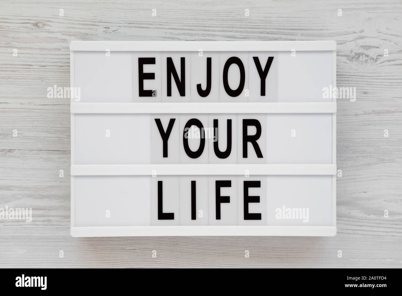 'Enjoy your life' words on a modern board over white wooden background ...