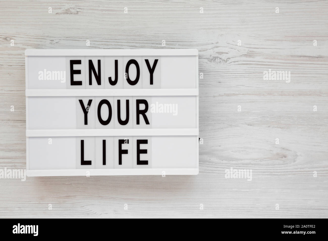 'Enjoy your life' words on a modern board over white wooden background ...