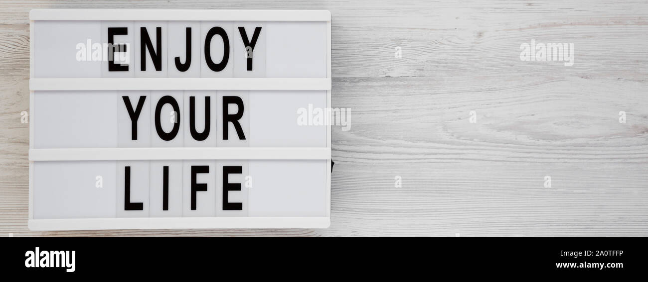 'Enjoy your life' words on a modern board over white wooden background ...