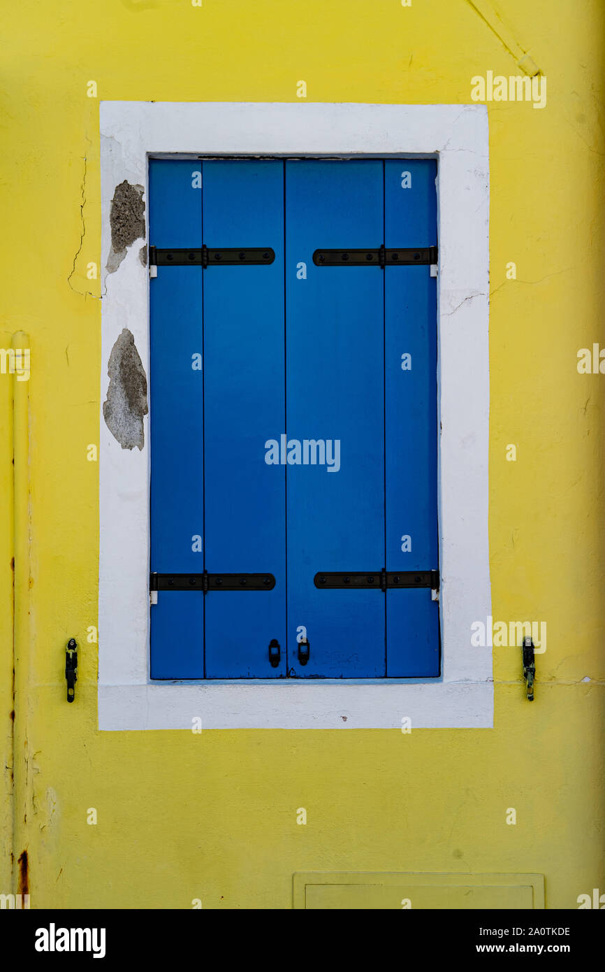 Blue shutter on a yellow wall. Colourful houses on the island of Burano ...
