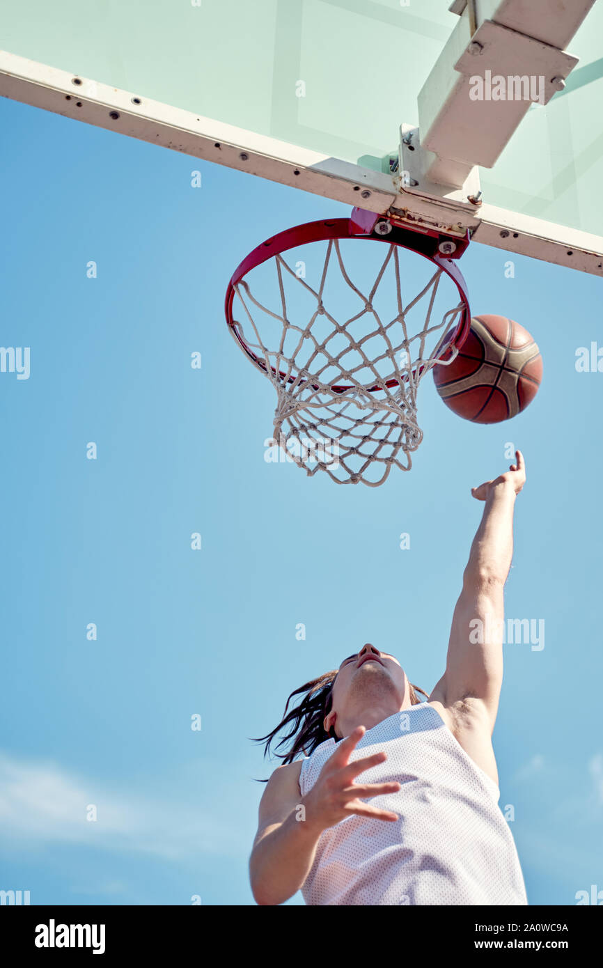 Photo of athlete man throwing ball into basketball hoop on sports field ...