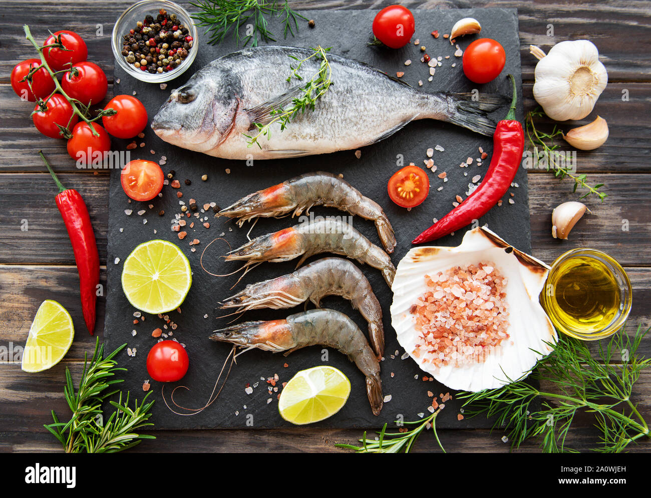 Fresh raw prawns, dorado fish and spices on black stone background ...
