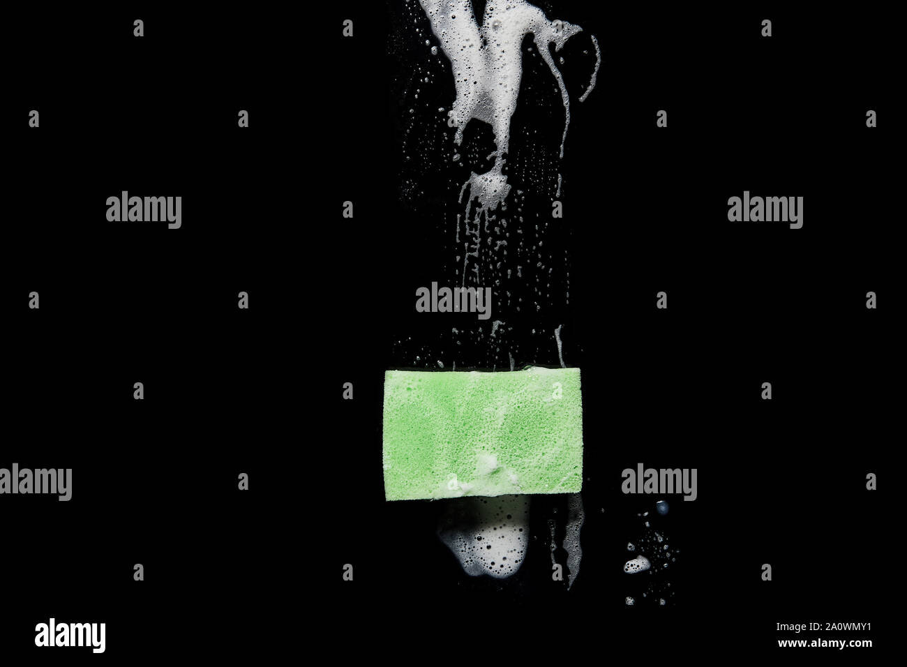 top view of green and colorful sponge with foam on black background ...