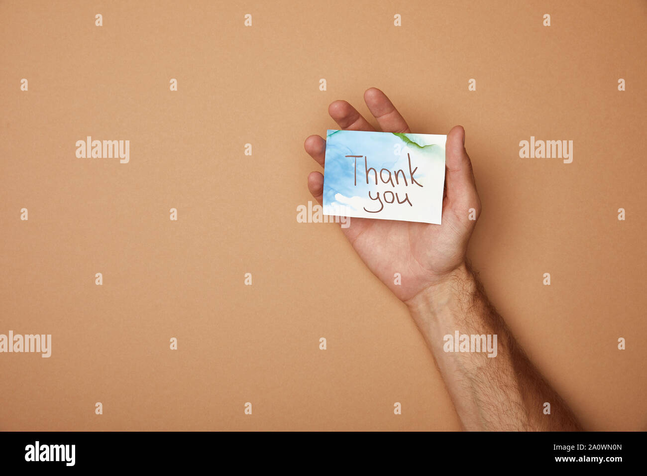 cropped view of man holding greeting card with thank you lettering on ...