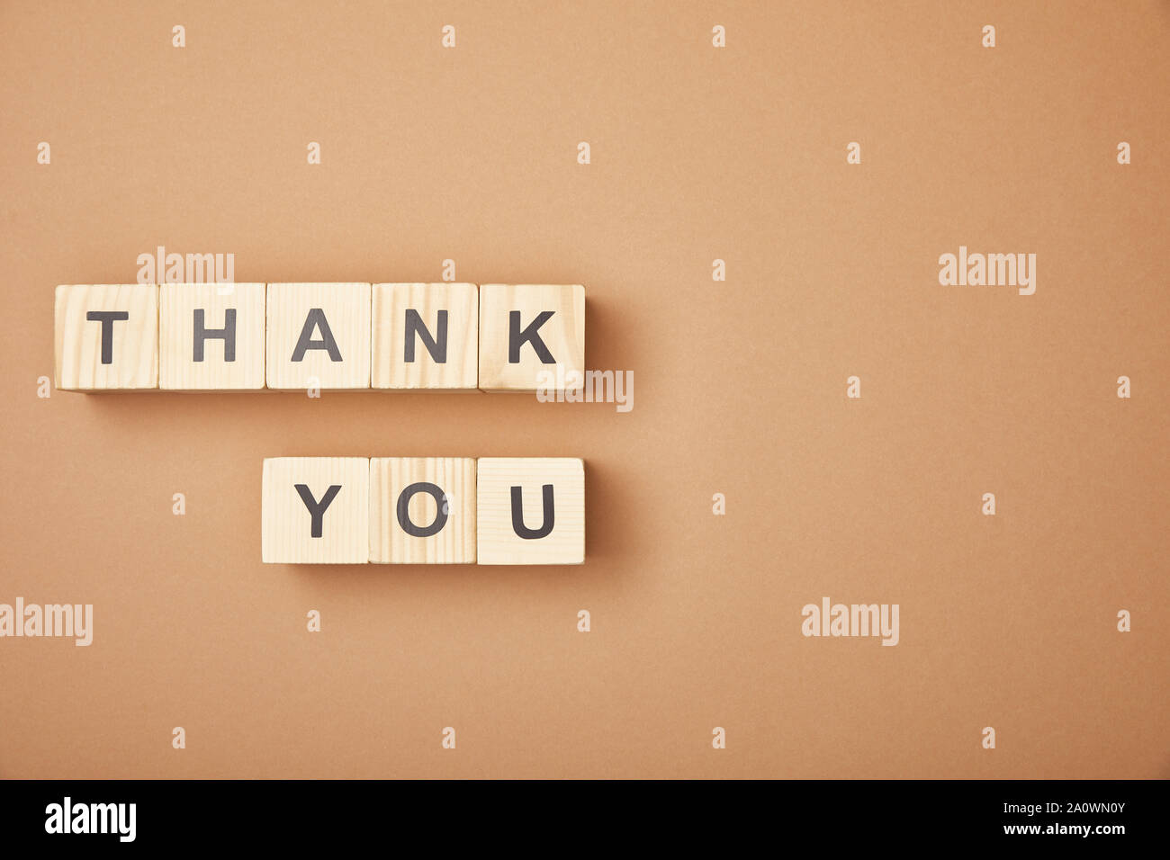 top view of wooden cubes with thank you lettering on beige background ...
