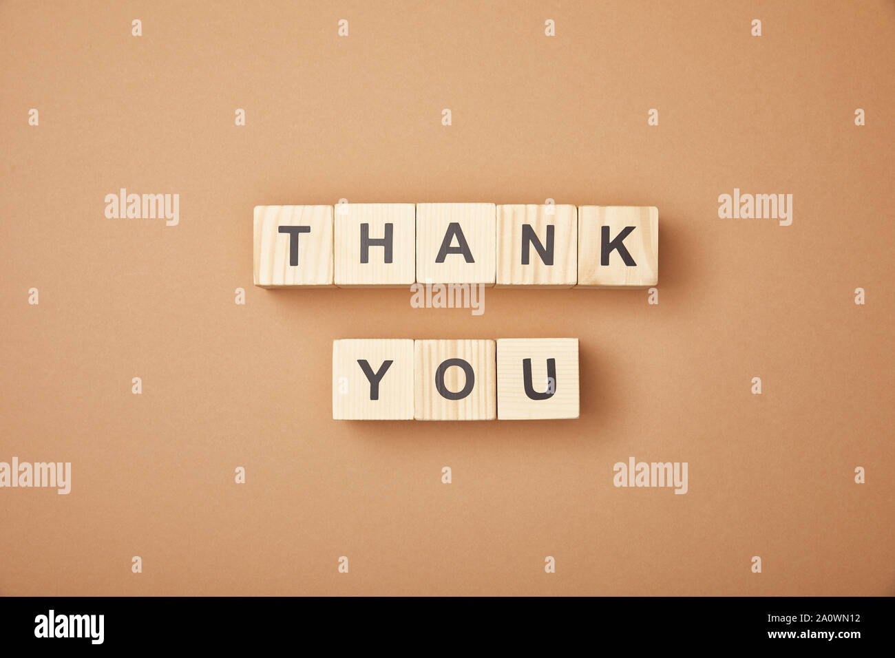 top view of wooden cubes with thank you lettering on beige background ...