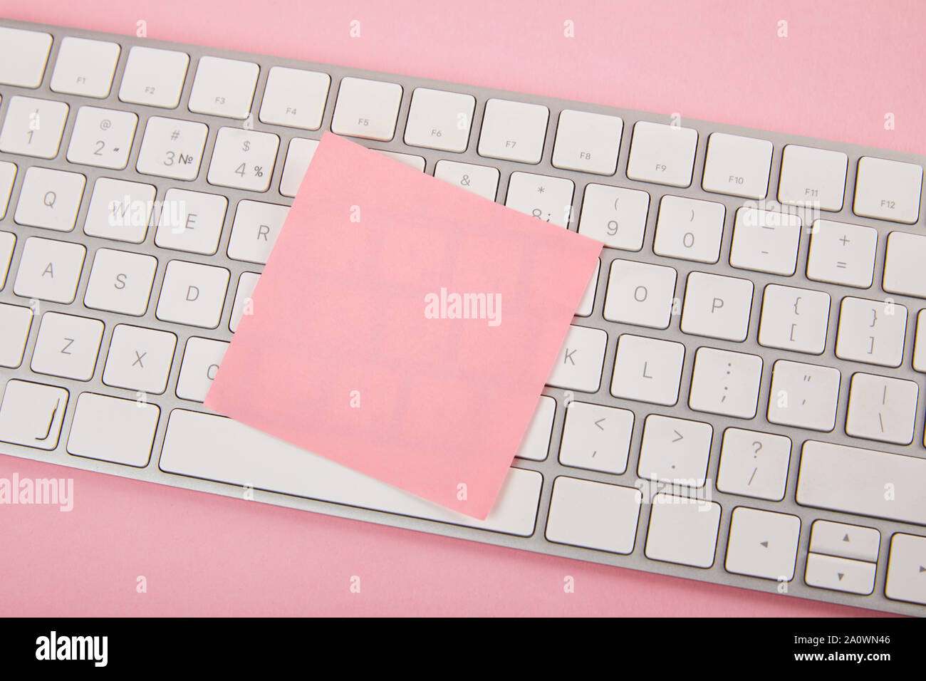 top view of empty pink sticky note on laptop keyboard on pink ...