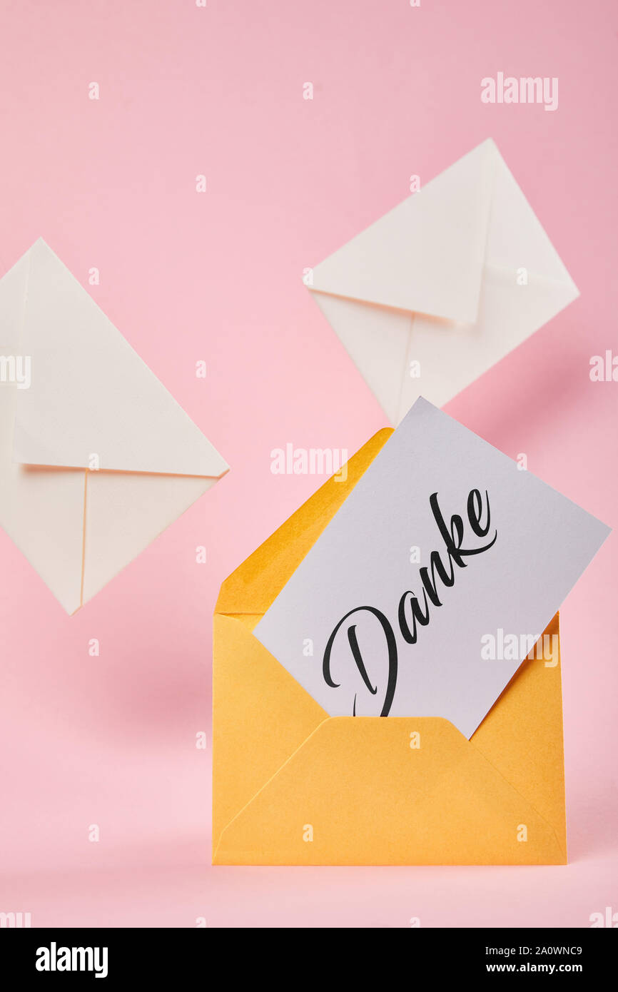 yellow envelope with danke word on white card near letters on pink ...