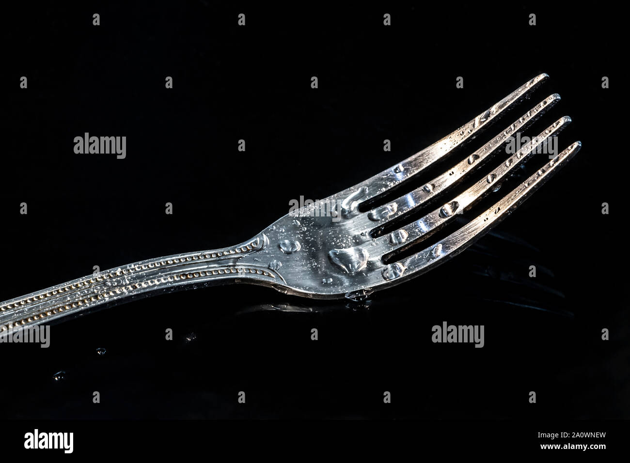 Single fork at the black table with water droplets on it Stock Photo ...