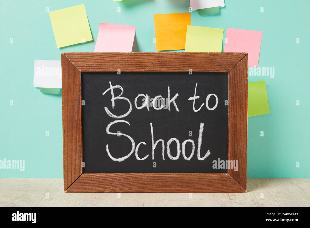 chalkboard with back to school lettering near multicolored sticky notes ...