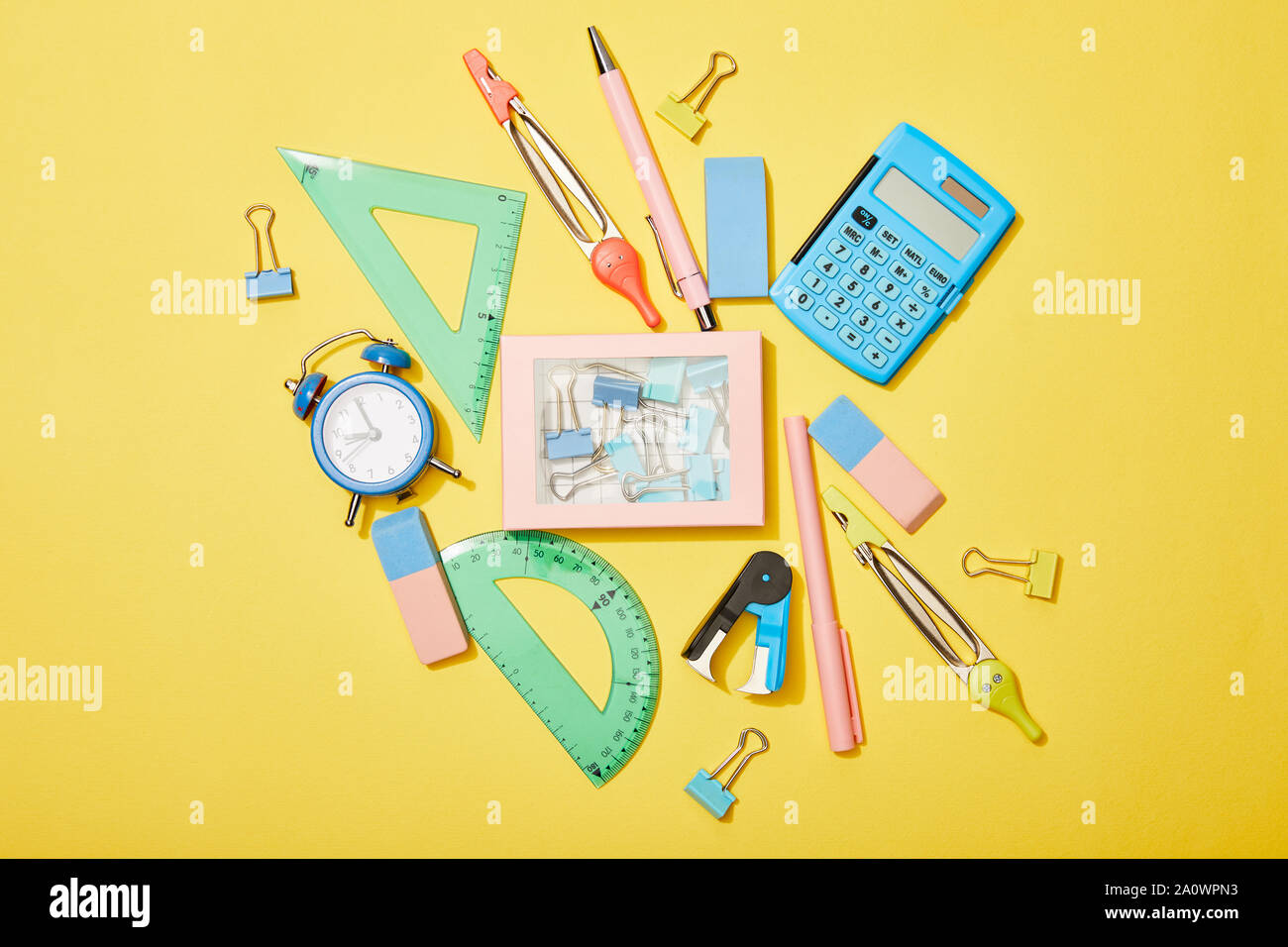 top view of school supplies scattered near box with clips on yellow ...