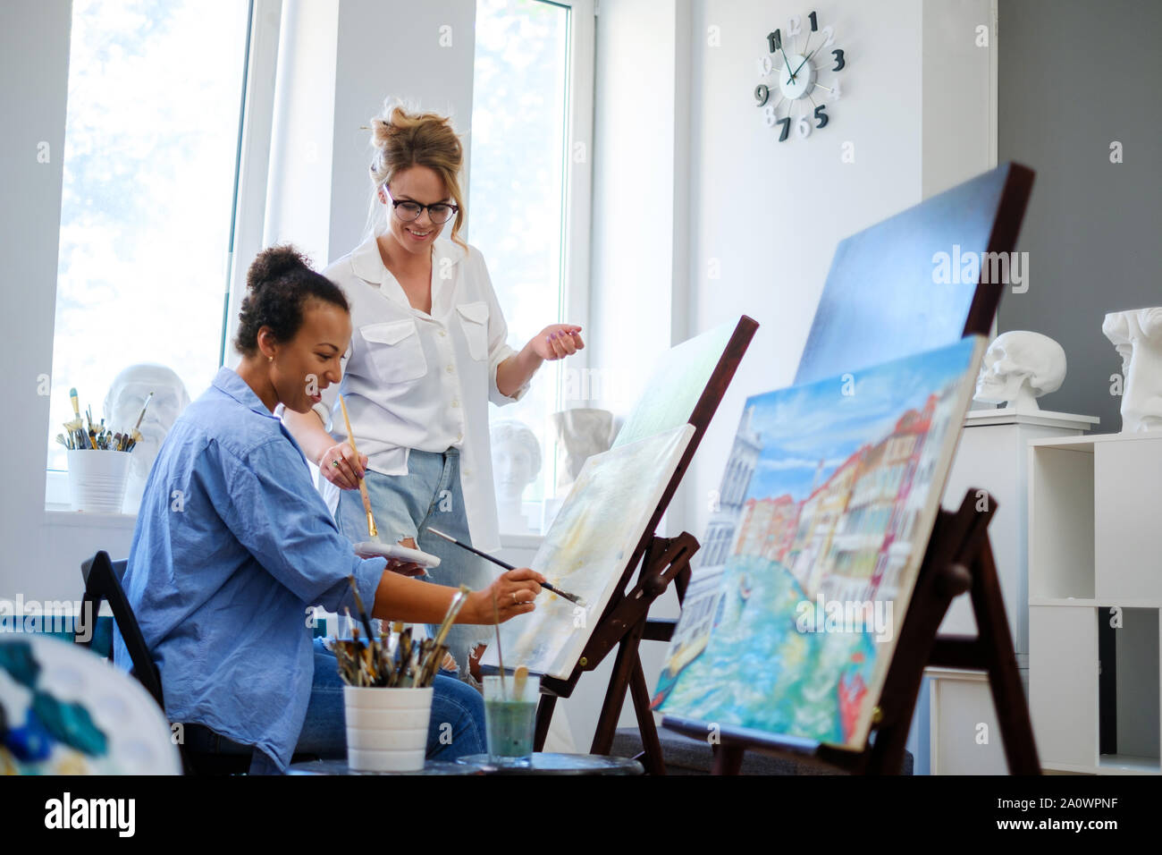 Creative painter and her protege working in a studio Stock Photo - Alamy