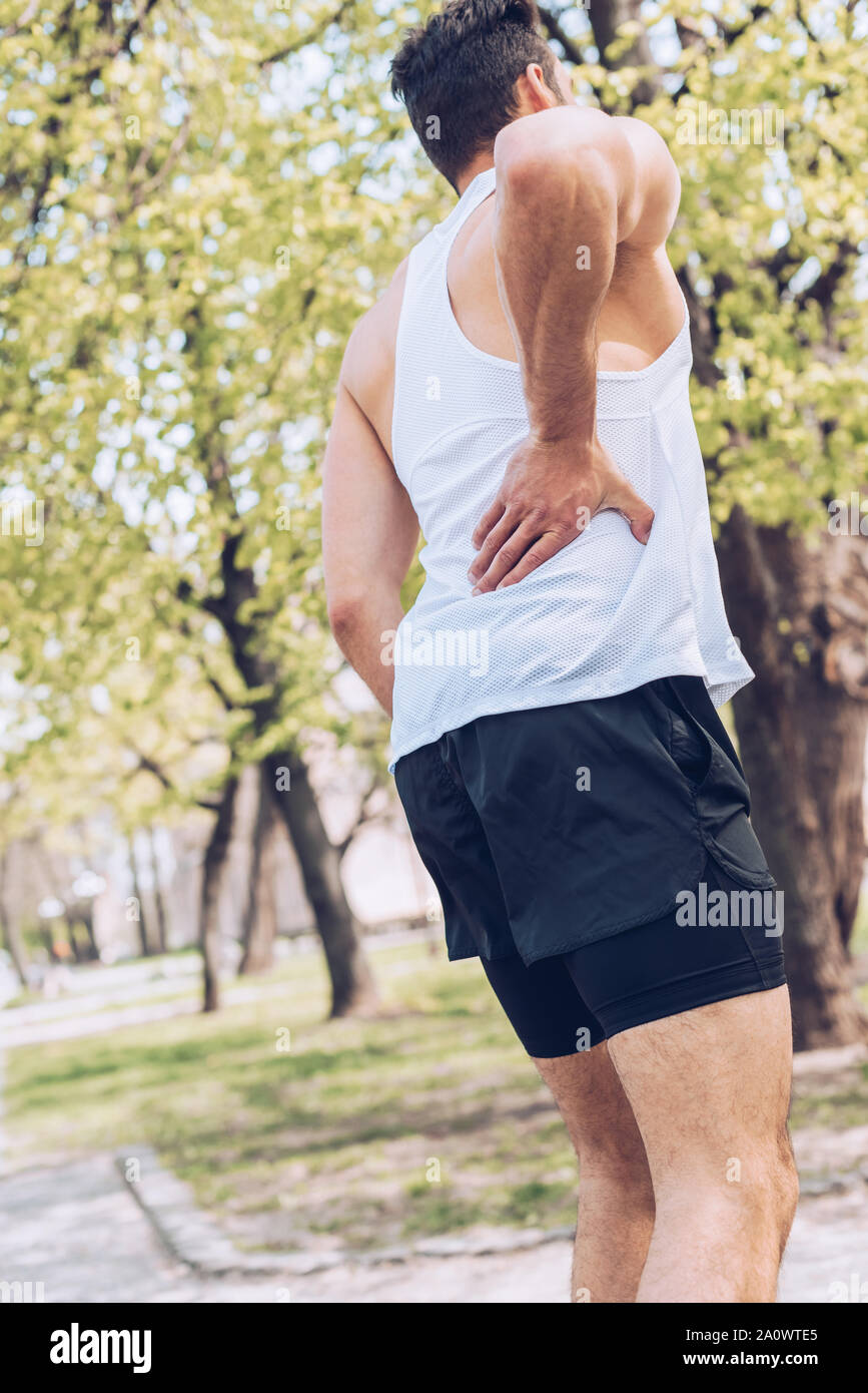 young sportsmen suffering from pain while touching injured back Stock ...