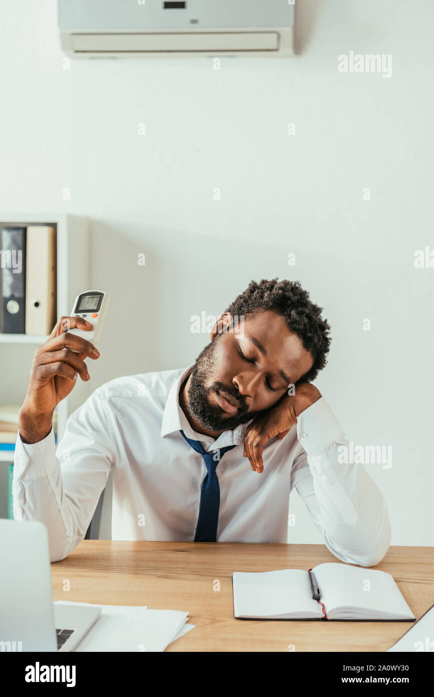 exhausted african american businessman sitting with closed eyes and ...