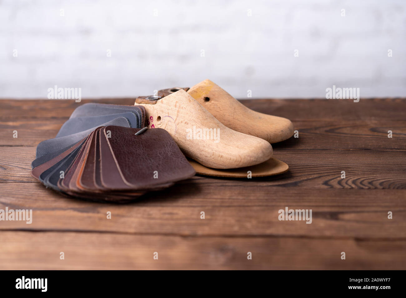 Leather samples for shoes and wooden shoe last on dark wooden table ...