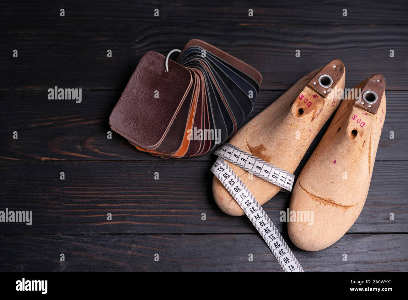 Leather samples for shoes and wooden shoe last on dark wooden table ...