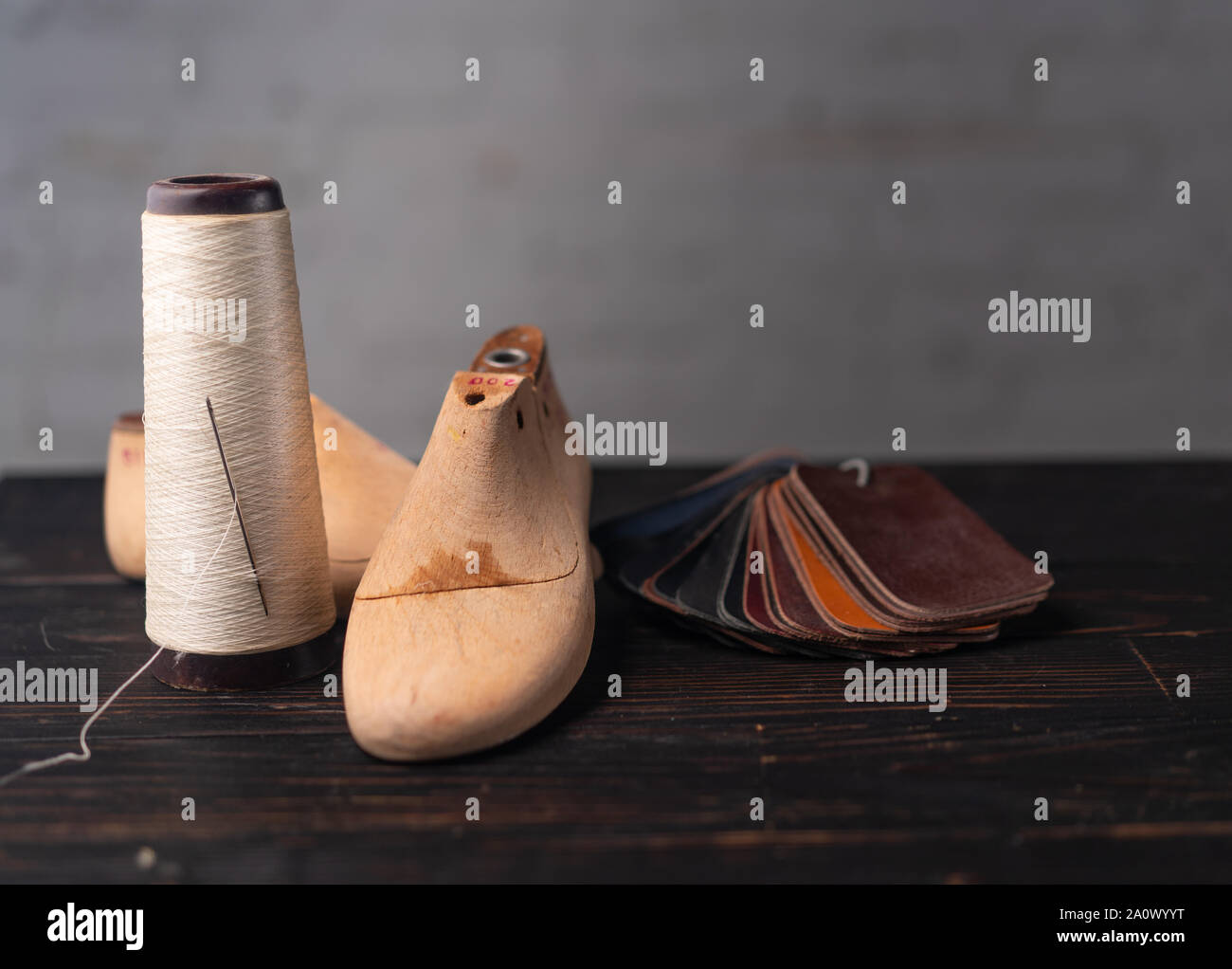 Leather samples for shoes and wooden shoe last on dark wooden table ...