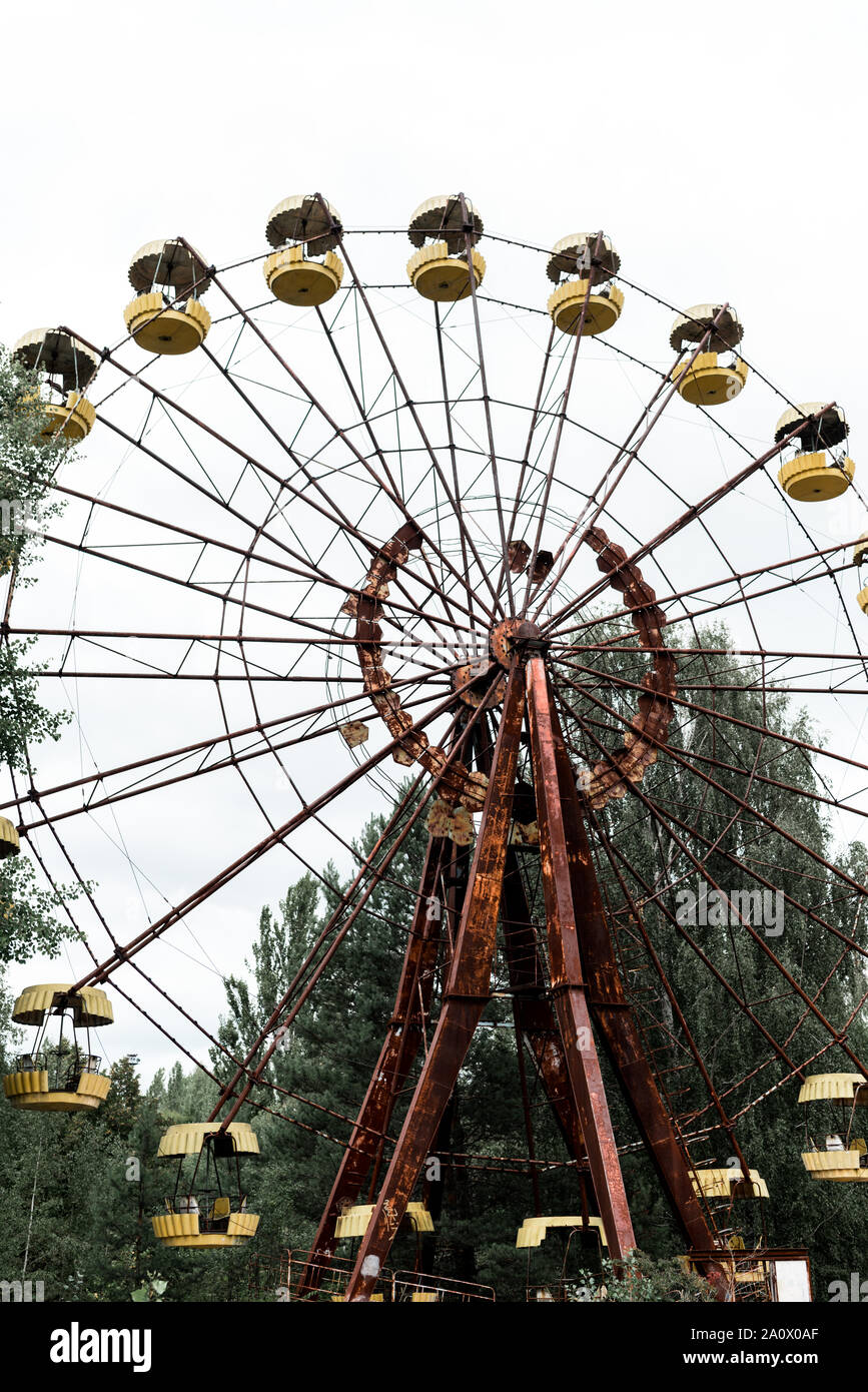 abandoned and rusty carousel in amusement park with trees against sky ...