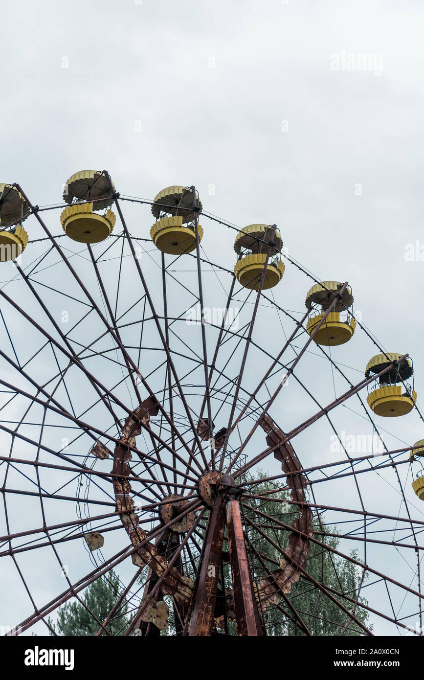 abandoned and rusty ferris wheel in green amusement park against blue ...