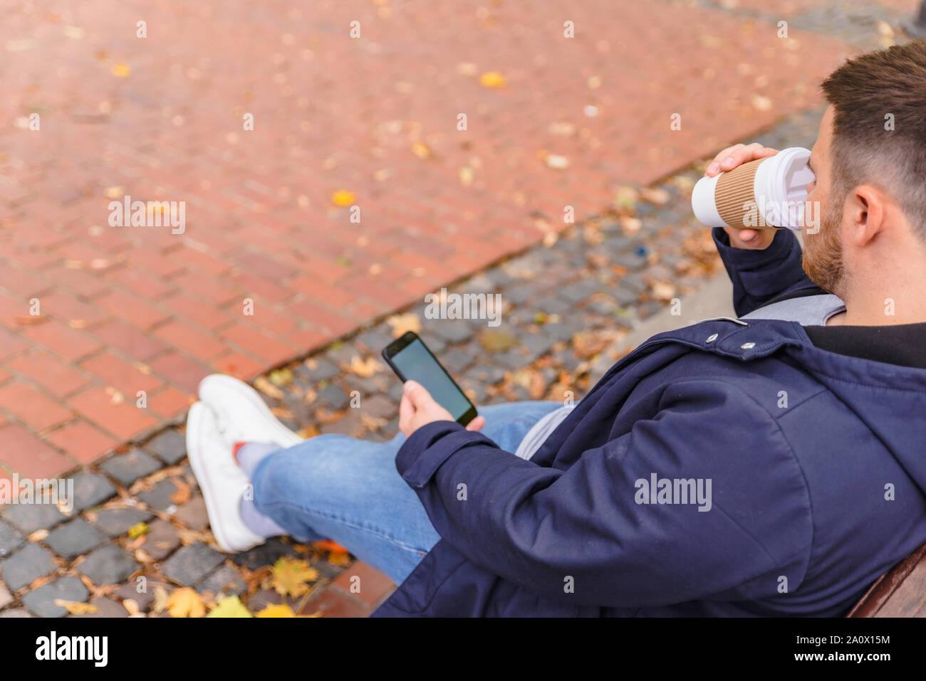 no face man sitting on the bench at city park drinking coffee surfing ...