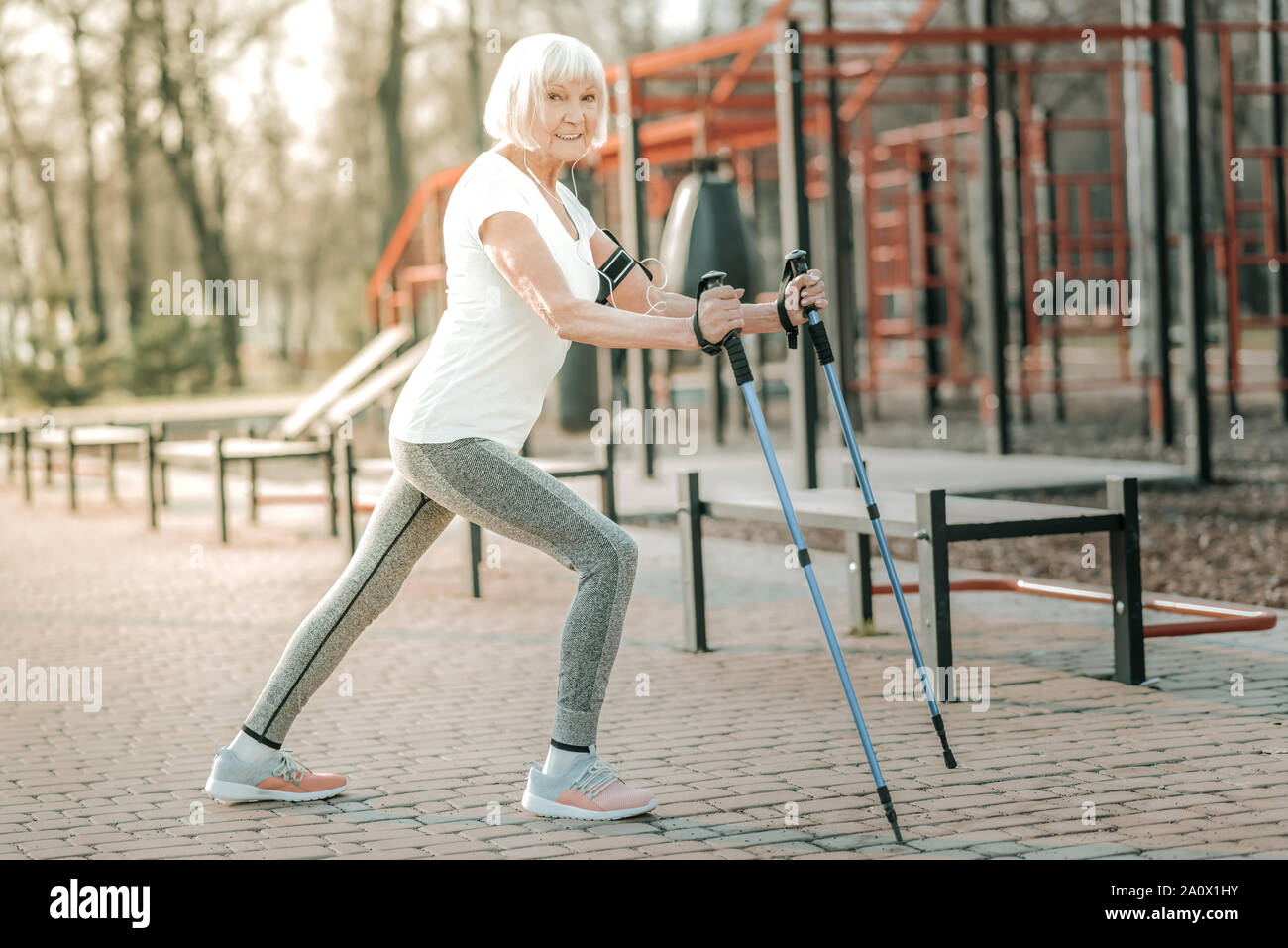 Madam in advanced years doing long steps with walking poles Stock Photo ...