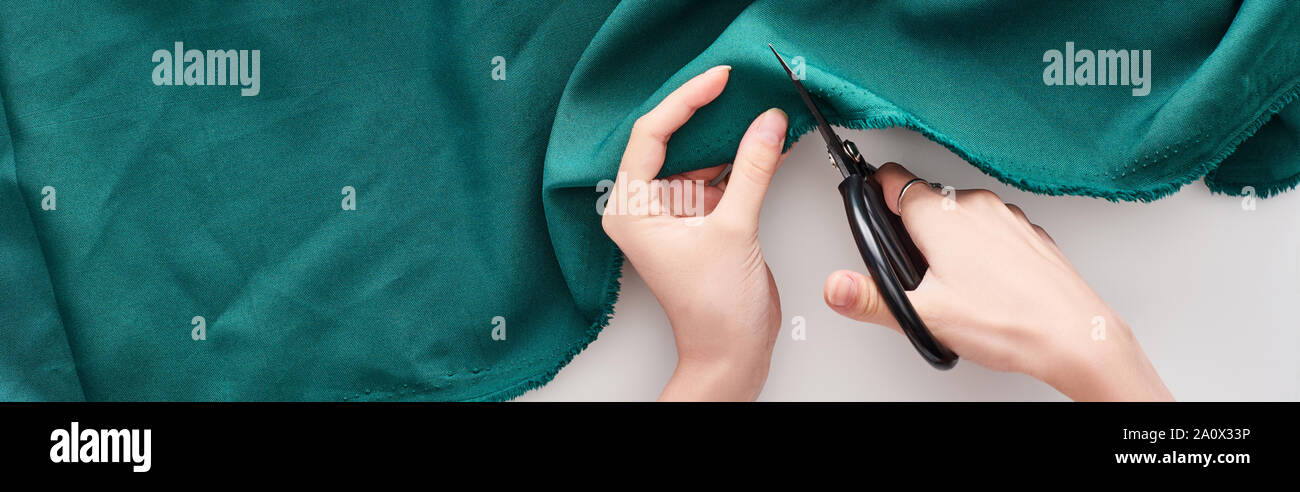 panoramic shot of seamstress cutting colorful fabric with scissors on ...