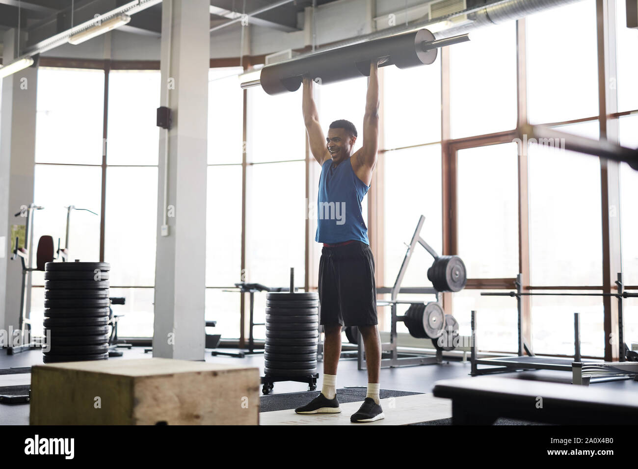 Full length portrait of muscular African-American man lifting weights ...