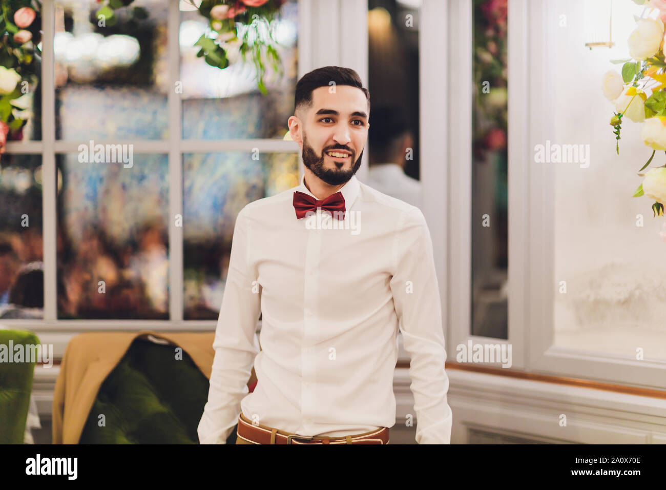 Happy handsome bearded groom in suit with a restaurant in background ...