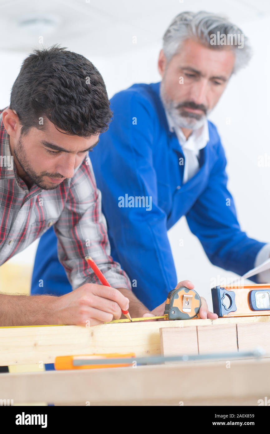 supervisor watching over your carpenter measuring wood Stock Photo - Alamy