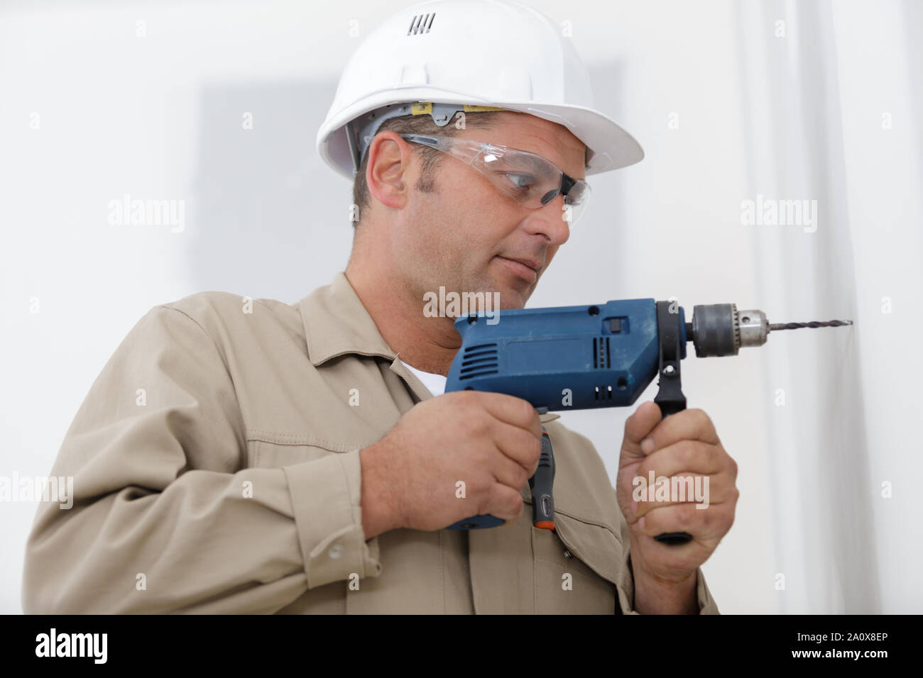 man drilling the wall with drill perforator Stock Photo - Alamy