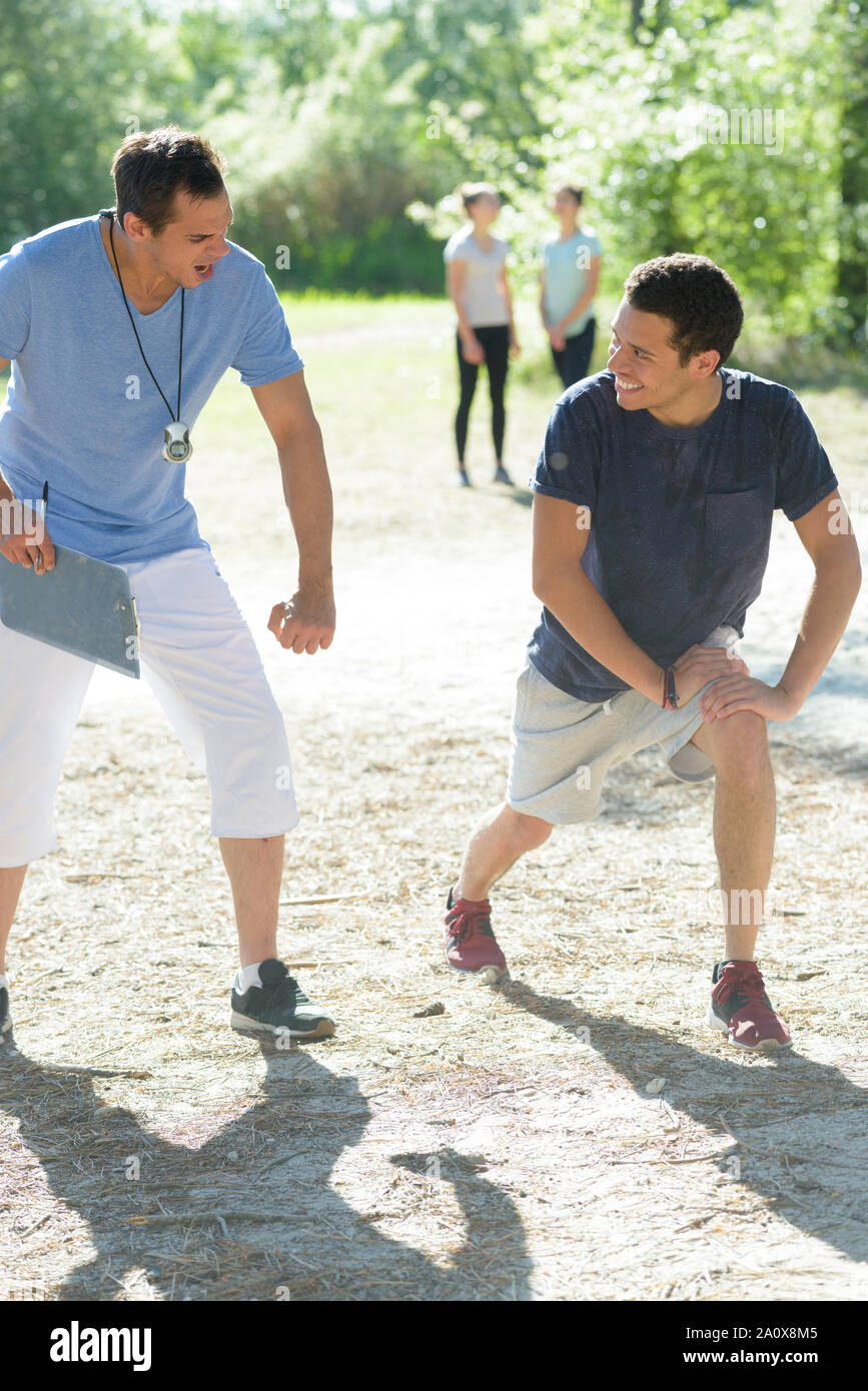 coach and sporty man stretching leg outdoors Stock Photo - Alamy