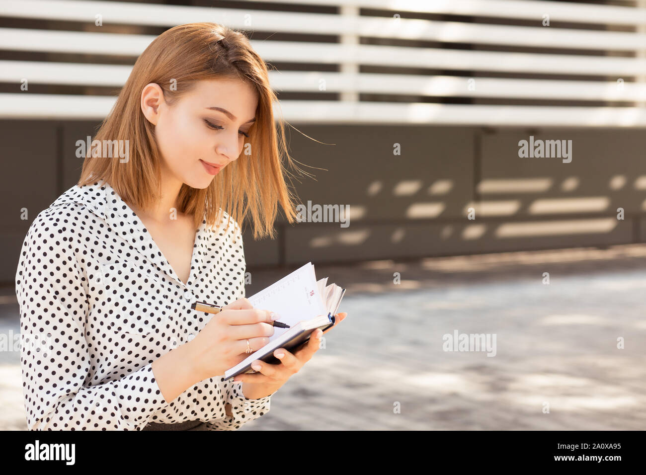 Happy woman with pencil writing in notebook working outdoor. Girl ...