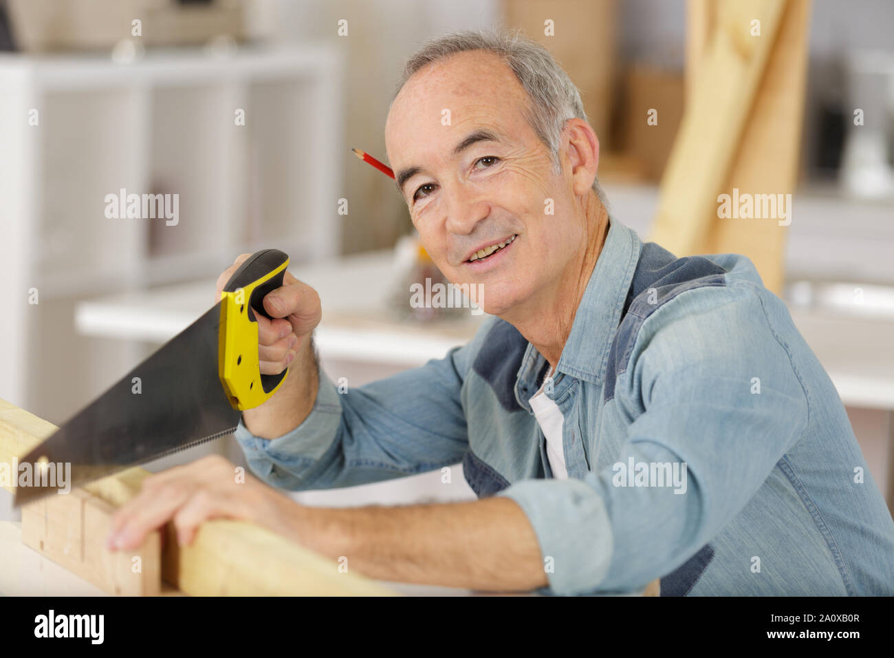 senior man with a handsaw cutting wood Stock Photo - Alamy