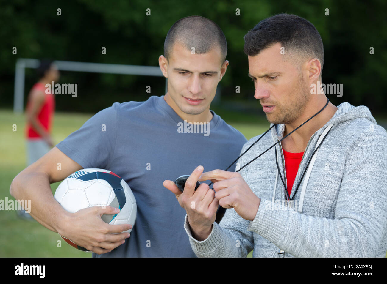 coach with footballer looking at stopwatch Stock Photo - Alamy