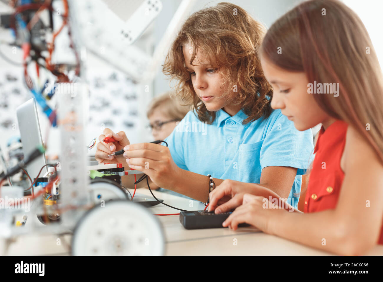 Robotics. Children sitting having class making robots girl helping ...