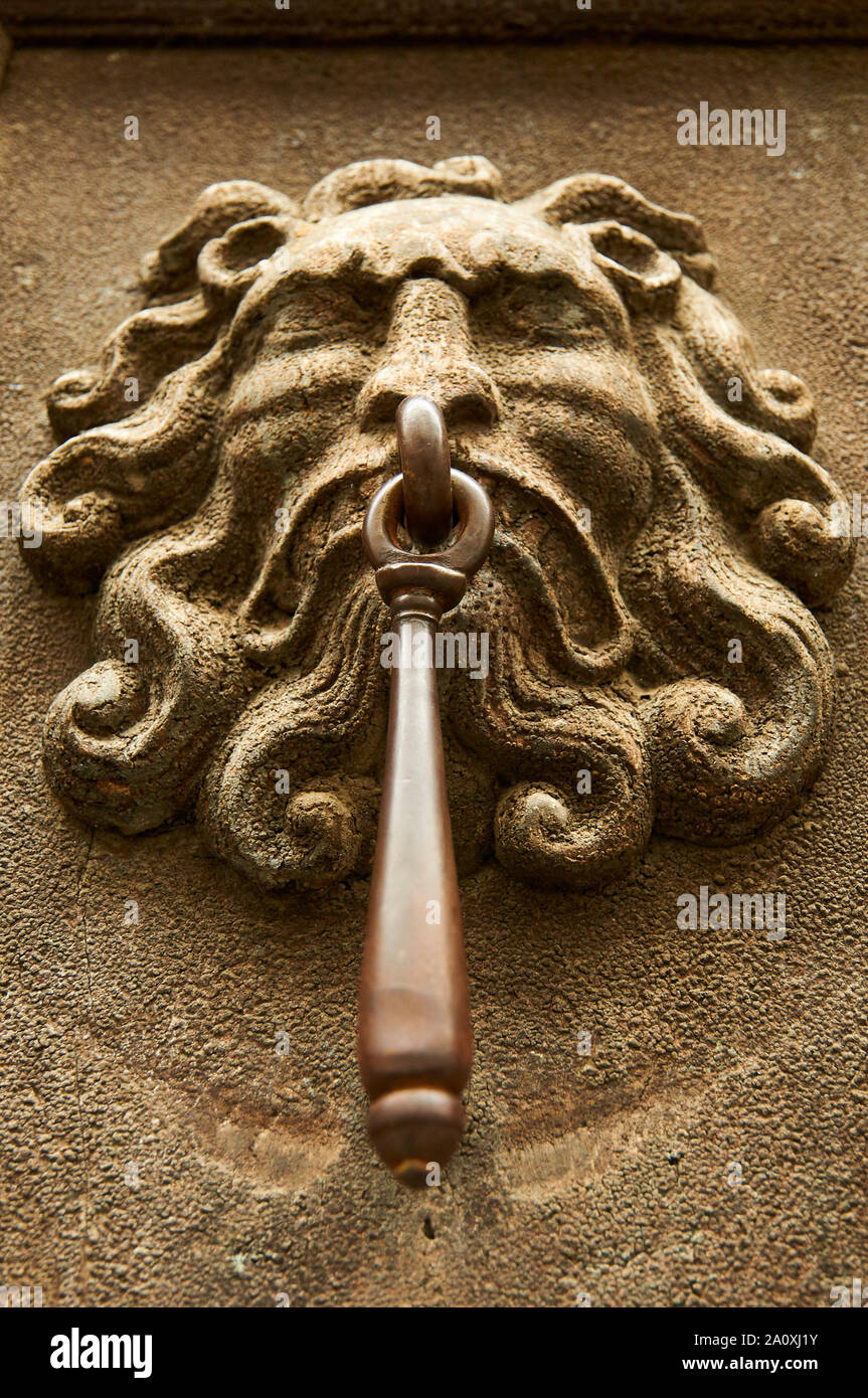Closeup of a human face door knocker in a vintage wood door of a house ...