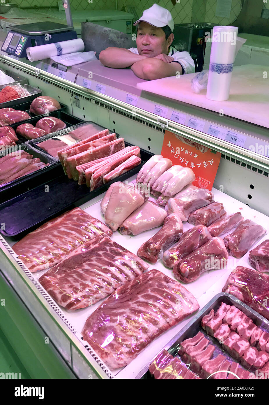 A Chinese pork butcher waits for customers at a local supermarket in ...