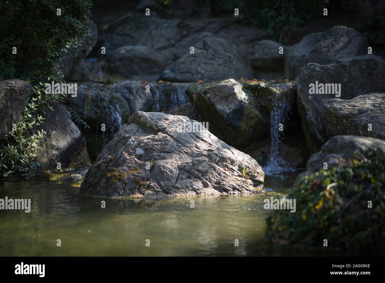 Rocks in a quiet creek in front of a small waterfall Stock Photo - Alamy