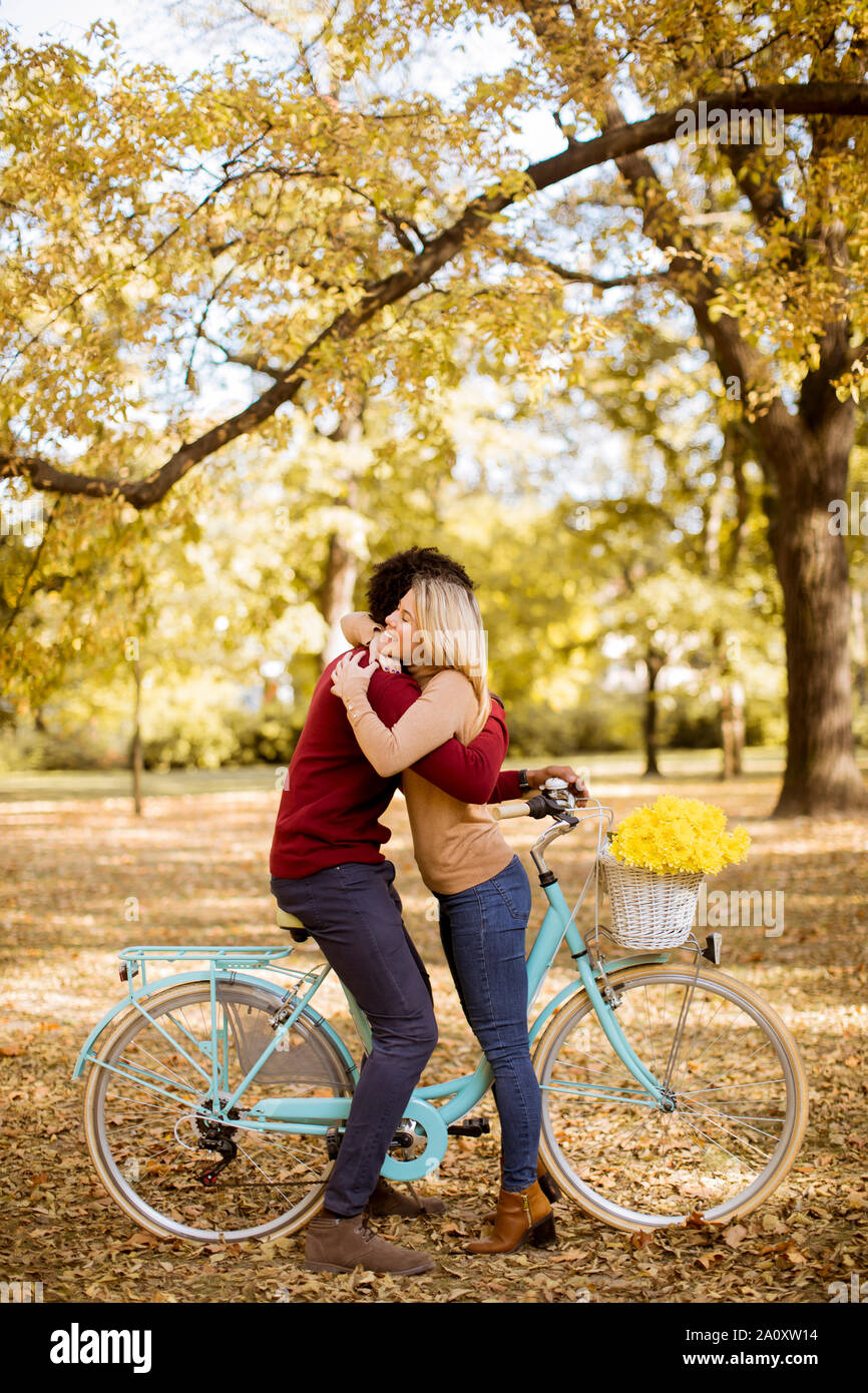 Multiracial young couple with bicycle standing in the autumn park Stock ...
