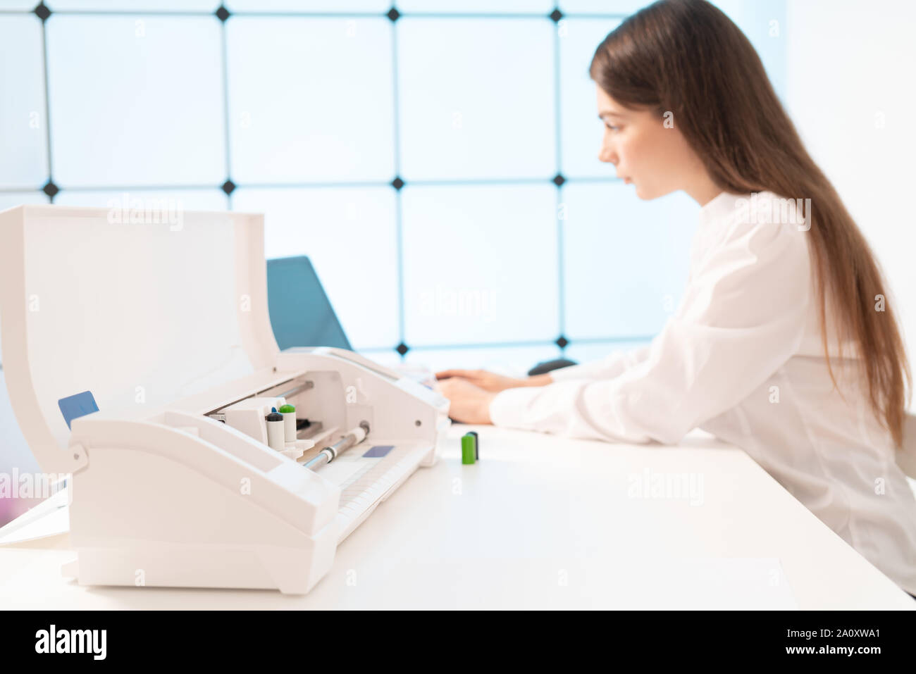 Young woman in the office of the printing company sets up a plotter for ...