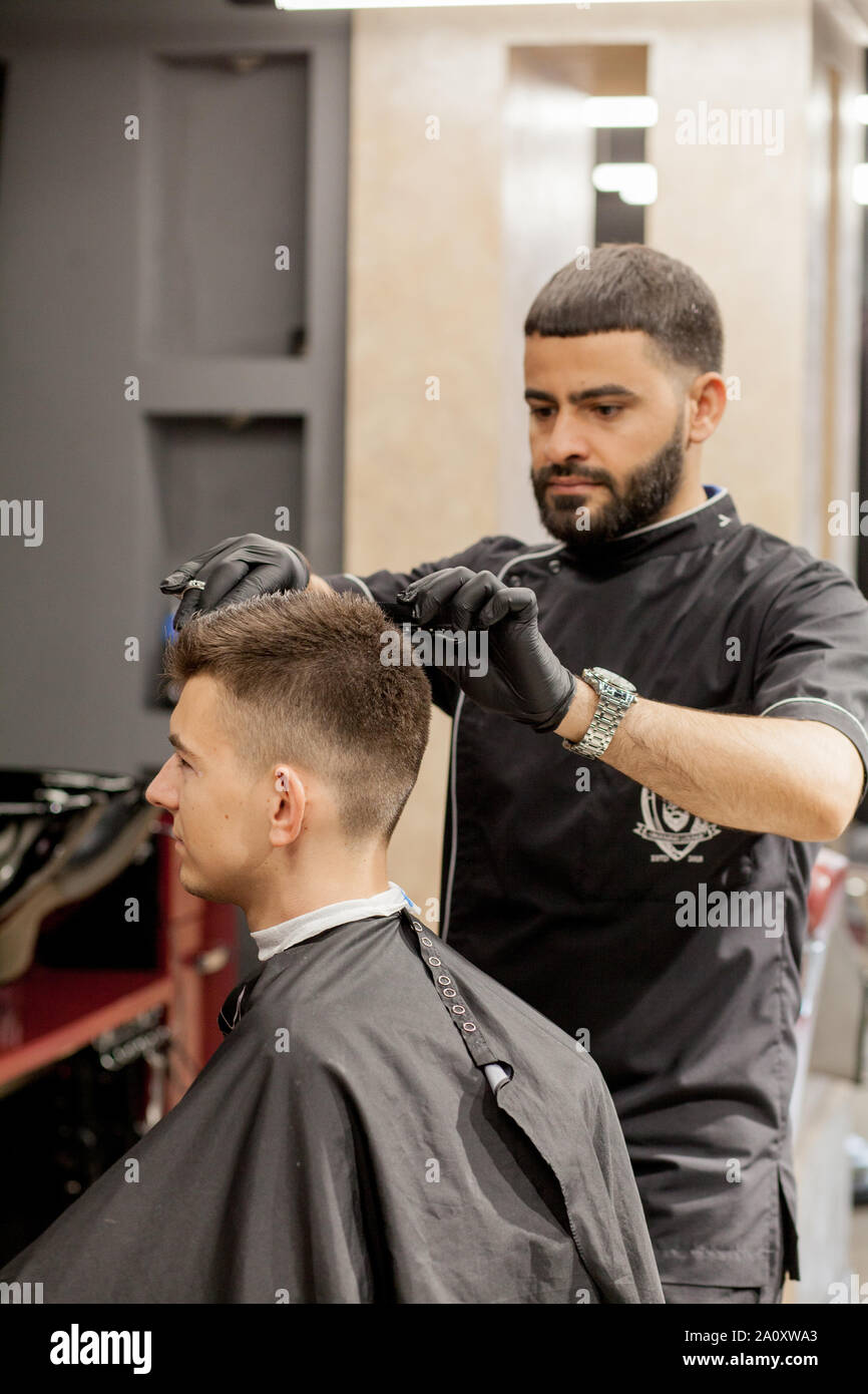 Brutal guy in modern Barber Shop. Hairdresser makes hairstyle a man ...