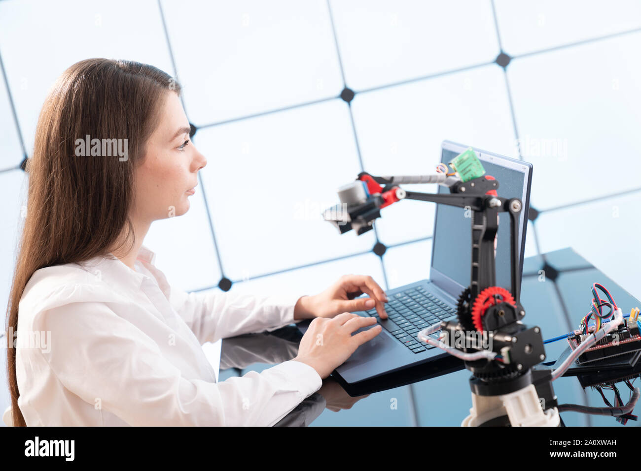 A young woman writes an algorithm for the robot arm. Science Research ...