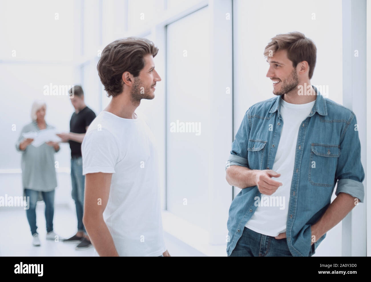 two colleagues talking standing in the office corridor Stock Photo - Alamy