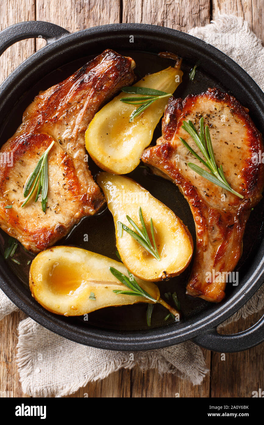 Baked pork chops with pears, rosemary and honey in a pan close-up on ...