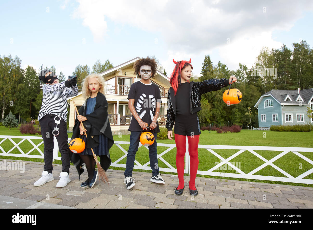 Multi-ethnic group of kids wearing Halloween costumes posing in street ...